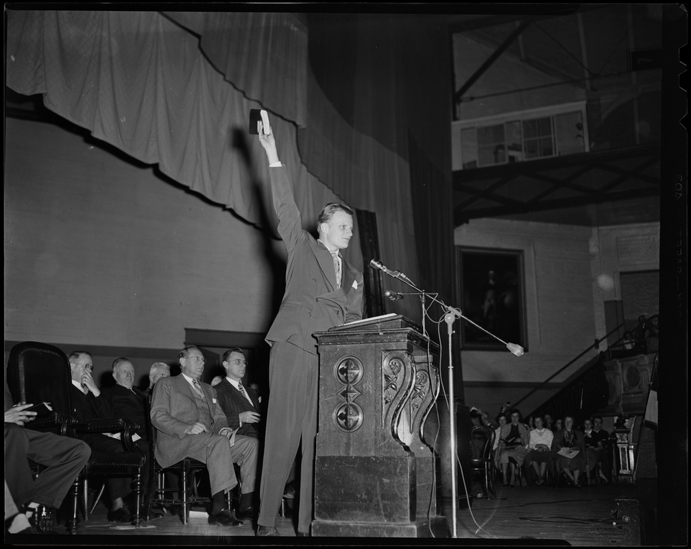 Billy Graham speaking at podium and holding up Bible - Digital Commonwealth