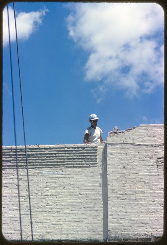 Construction worker standing on roof - Digital Commonwealth