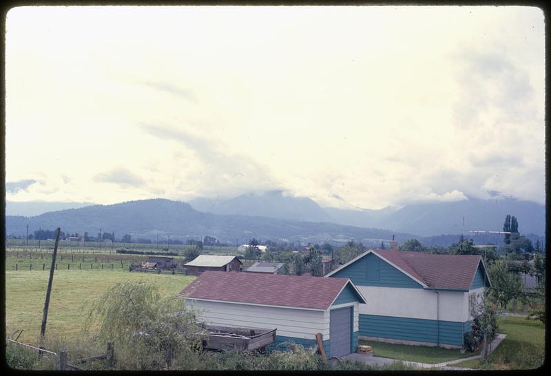 Farm buildings and fields with hills in background, British Columbia ...