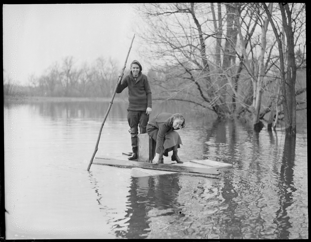 Couple poles through flood waters of makeshift raft - Digital Commonwealth