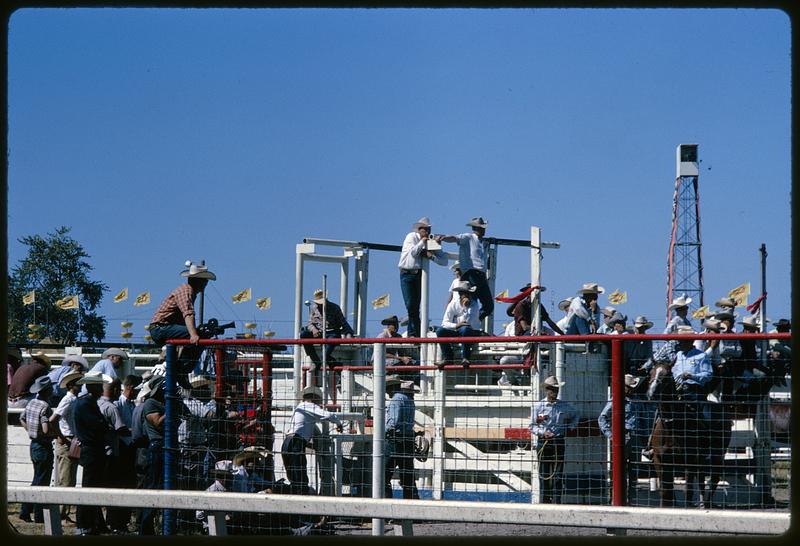 Men in cowboy hats standing on and around platform behind fence ...