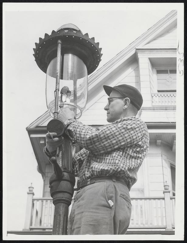 Modern Lamplighter -- He's James Flynn shown atop the crossbar of tis lamp on Wellesley place in ...
