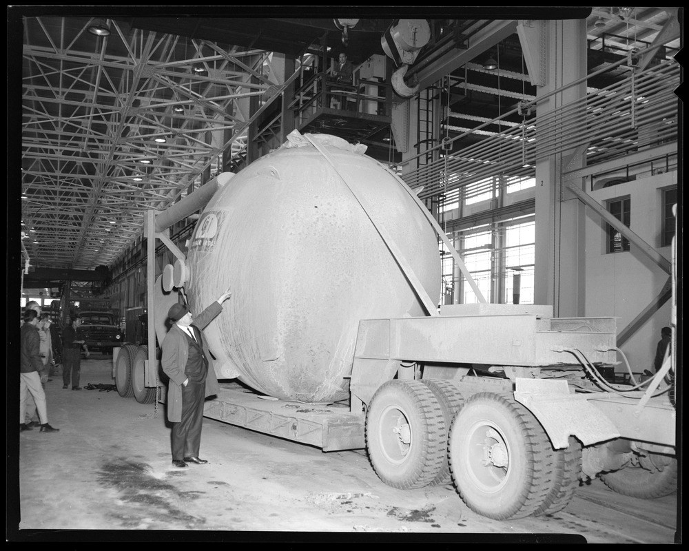 Man pointing at large round object on truck - Digital Commonwealth