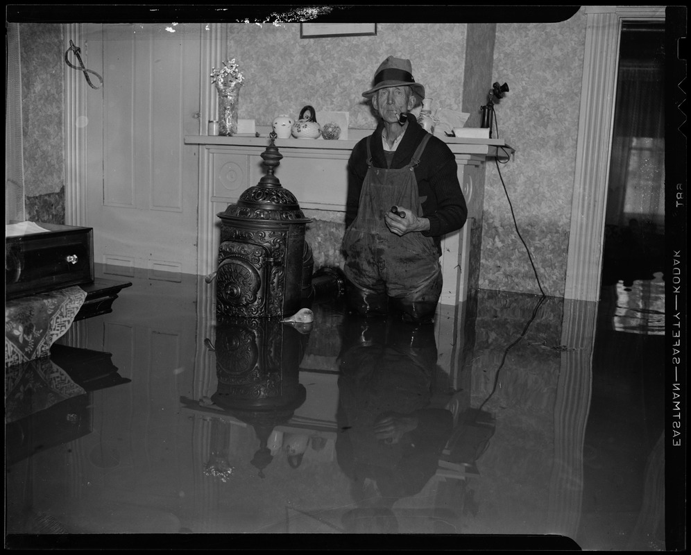 Man with pipe in flooded home, near fireplace with floating objects ...