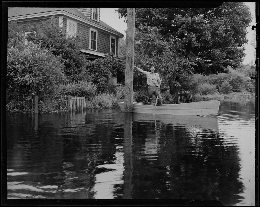 A young man in boat wading through flooded waters - Digital Commonwealth