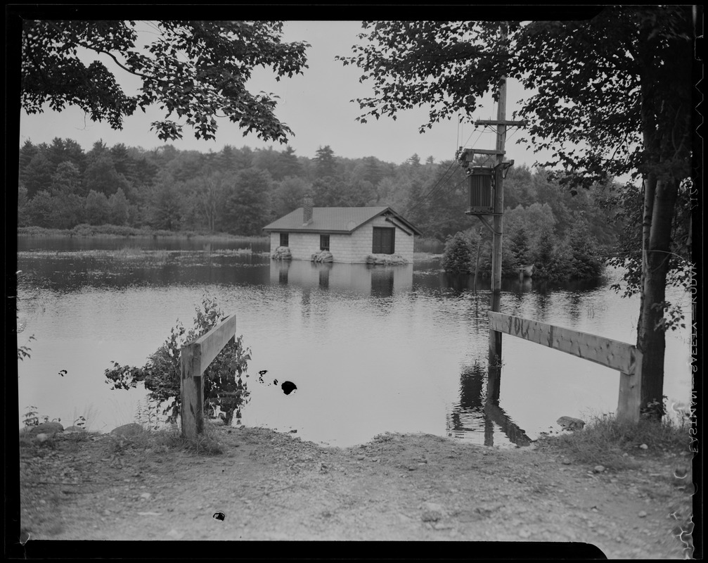 Cabin with sandbags surrounded by flooded water - Digital Commonwealth
