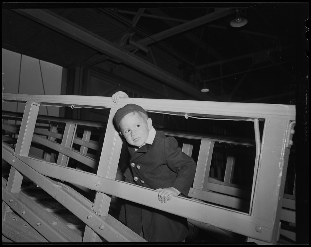 Young boy sticking his head in between the railings of the ship ...