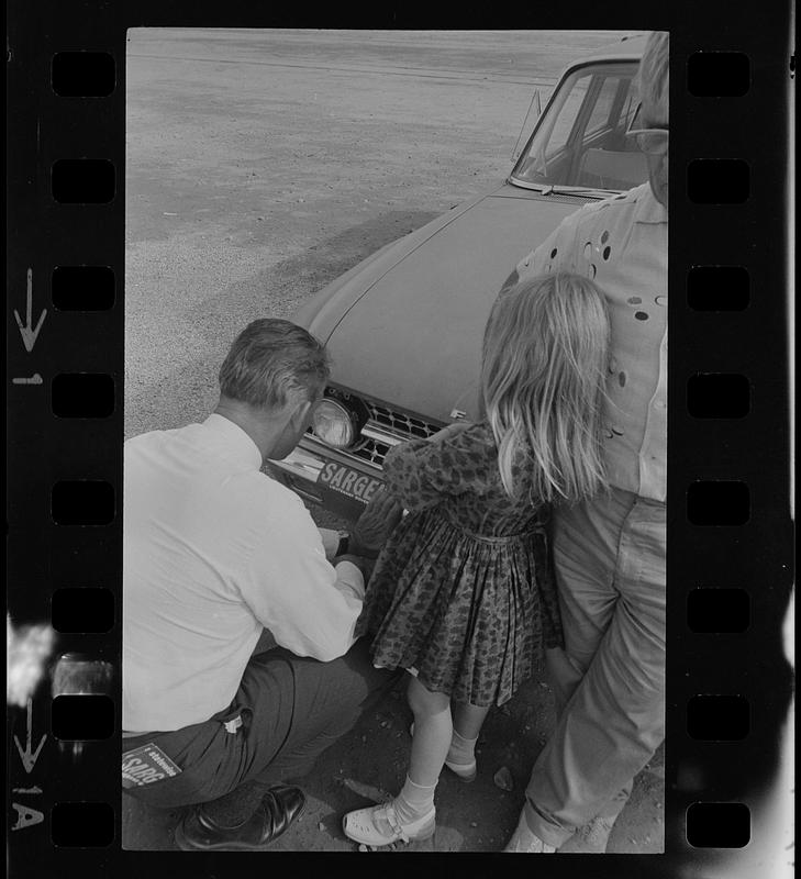 Man applying bumper sticker to automobile - Digital Commonwealth