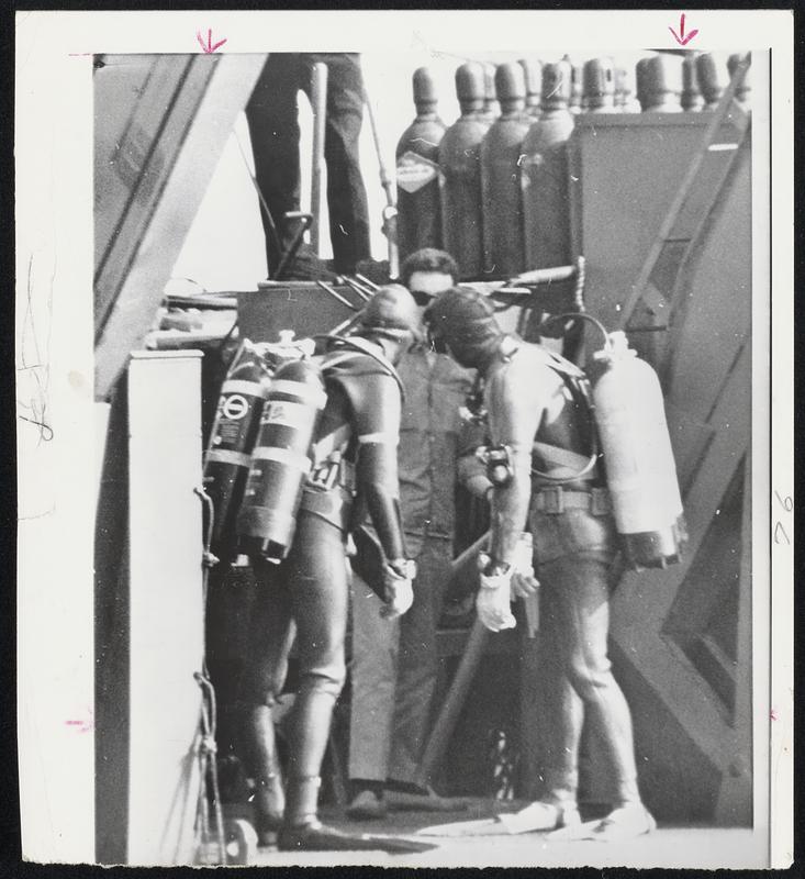 Two divers get instruction from salvage operator before they dive for ...