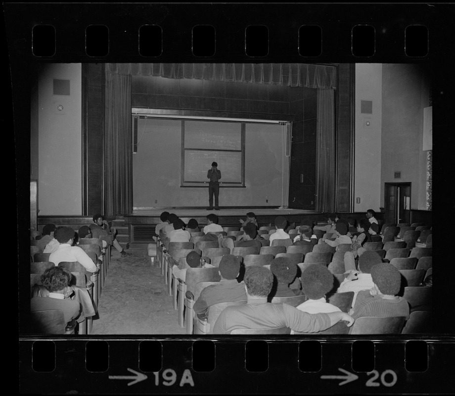 Black student protester on stage speaking to others in theater during ...
