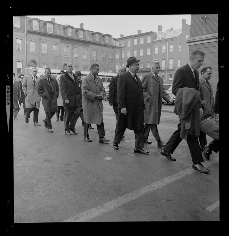 Group of men walking in line though a parking lot - Digital Commonwealth