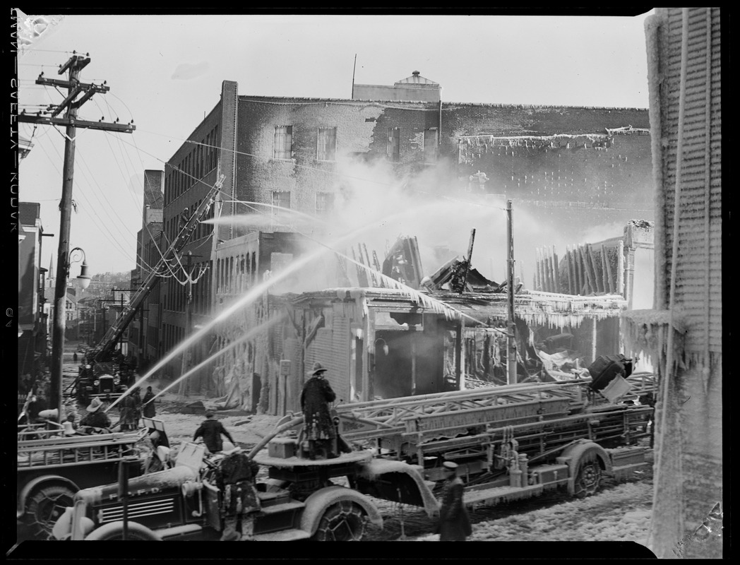 Firefighters using hoses from engines to put out a building fire ...