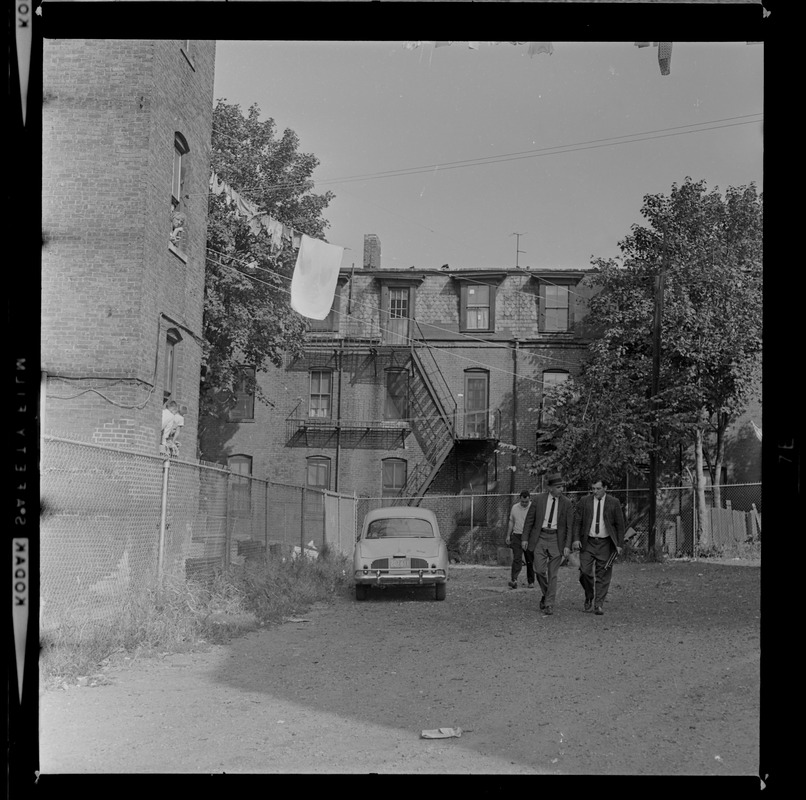 Police walking away from a vehicle behind a building - Digital Commonwealth