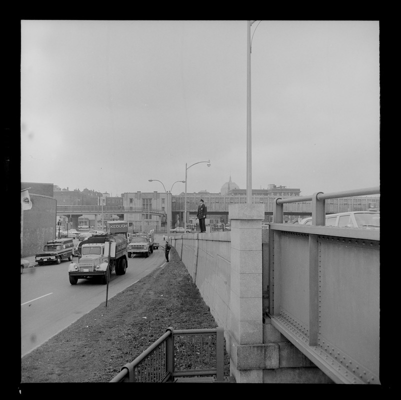 Street view with a police officers surveying along barrier wall ...