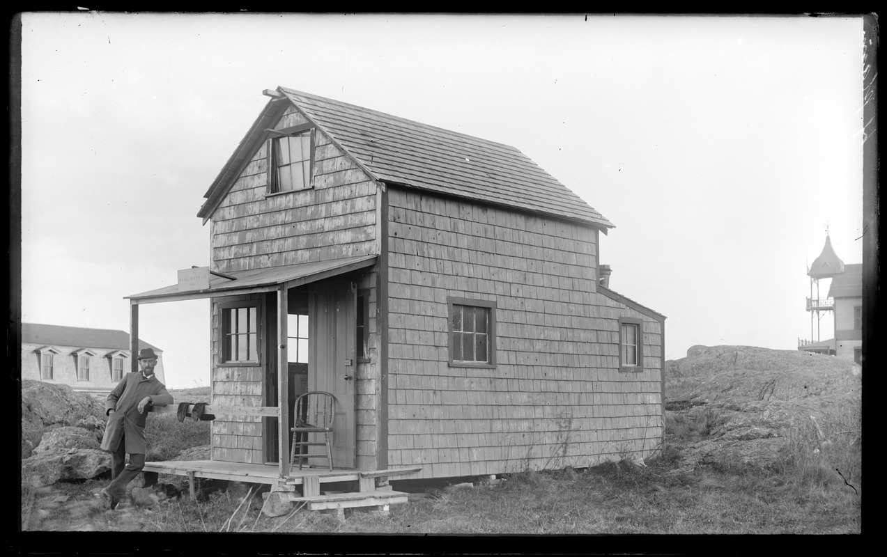 Man posing in front of small house or shed - Digital Commonwealth