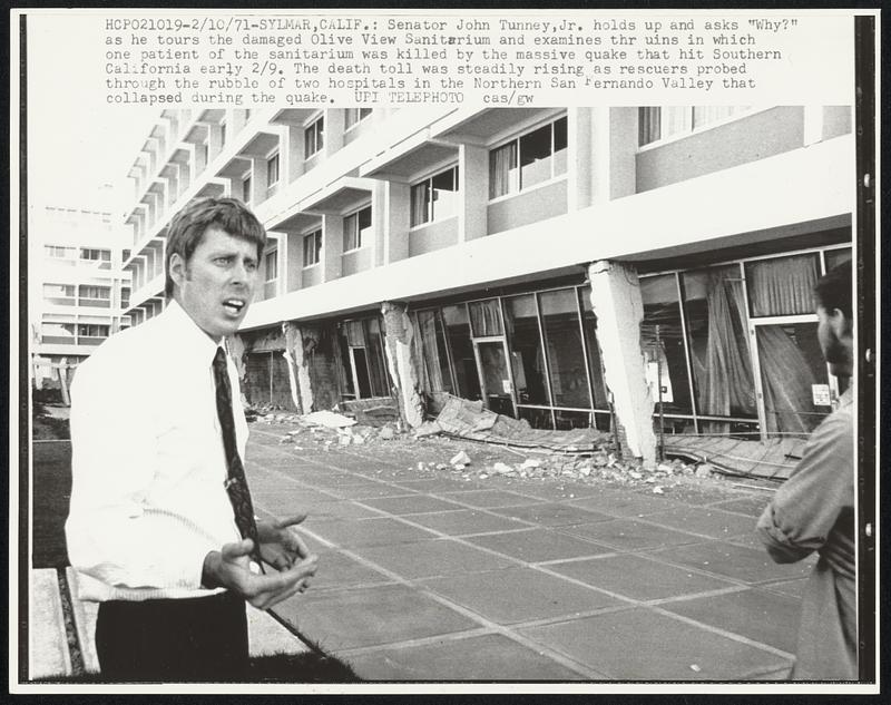 Senator John Tunney, Jr. holds up and asks "Why?" as he tours the ...