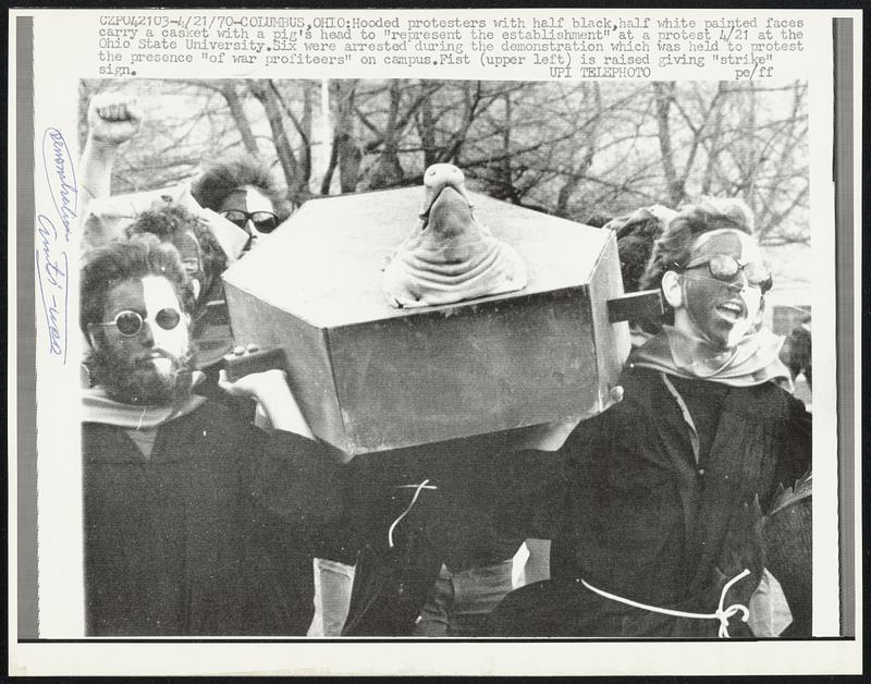 Hooded protesters with half black, half white painted faces carry a ...
