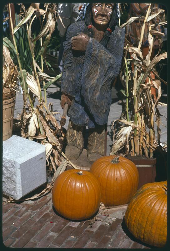Pumpkins next to a wood sculpture of a Native American man - Digital ...