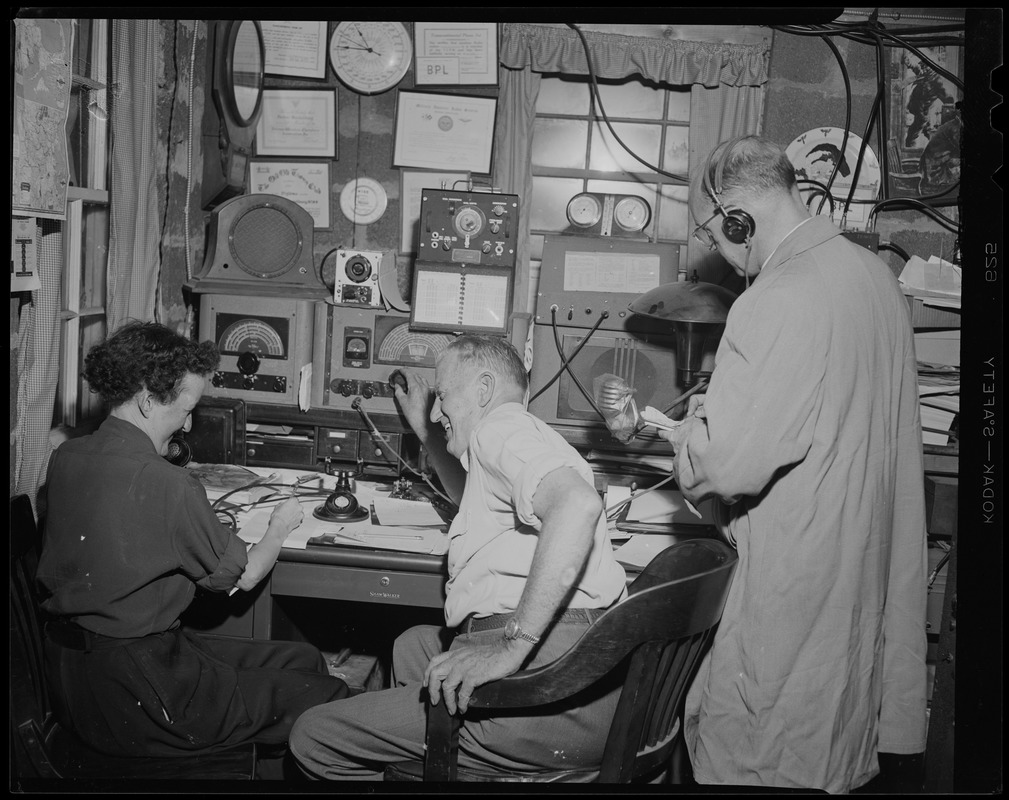 Three people using radio equipment at a desk - Digital Commonwealth