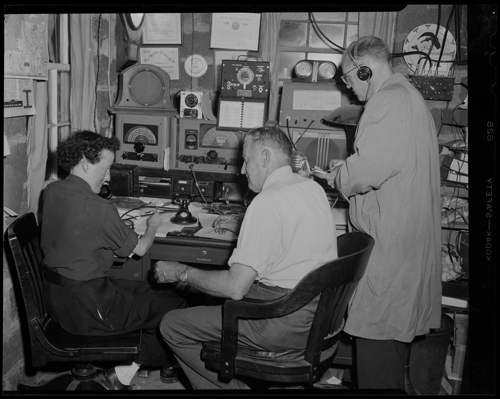 Three people using radio equipment at a desk - Digital Commonwealth