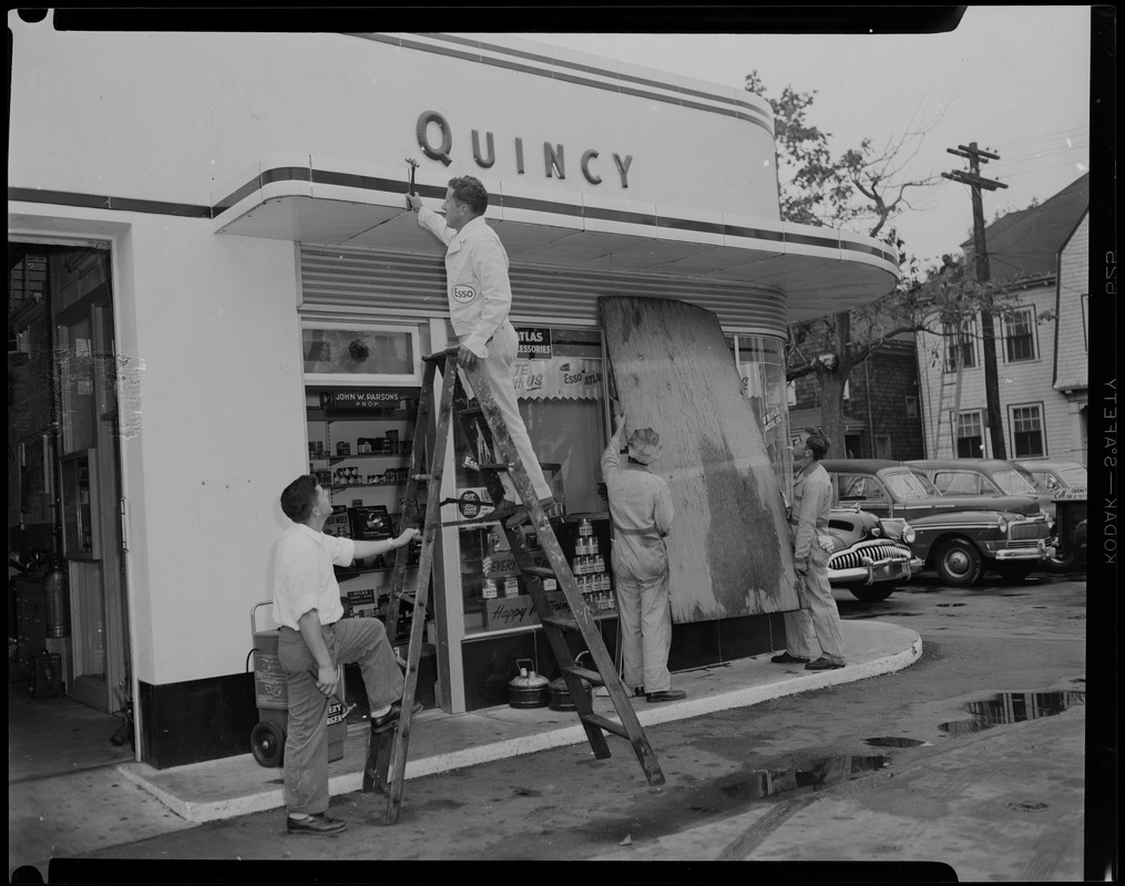 Four people boarding windows at Quincy gas station in preparation for ...