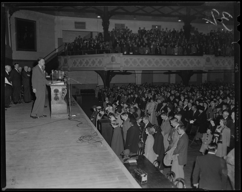 Billy Graham on stage addressing standing crowd at revival service ...