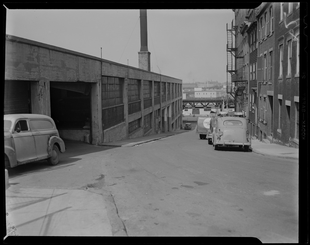 View of street with parked cars and garage - Digital Commonwealth