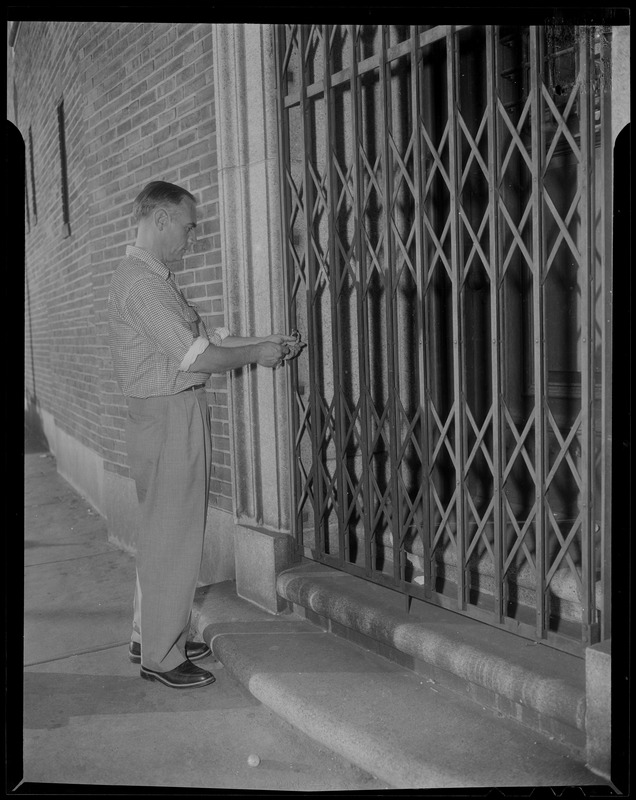 Man with keys locking or unlocking a gated security door at Charles ...