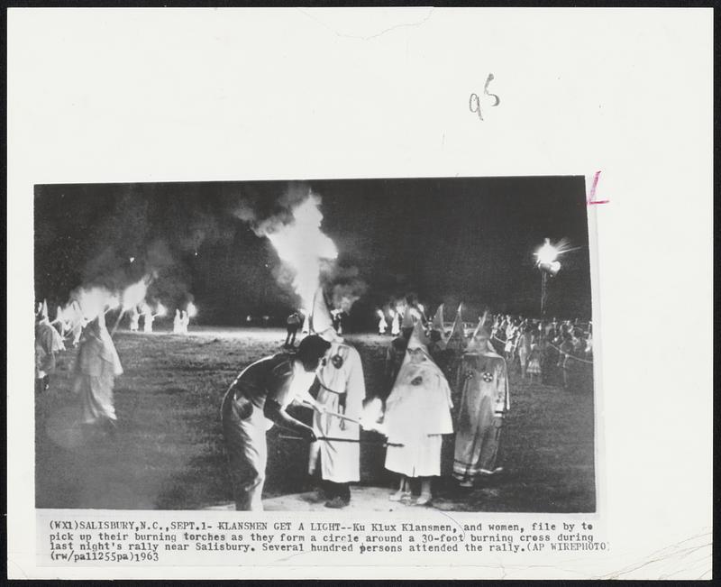 Klansmen Get a Light--Ku Klux Klansmen, and women, file by to pick up ...