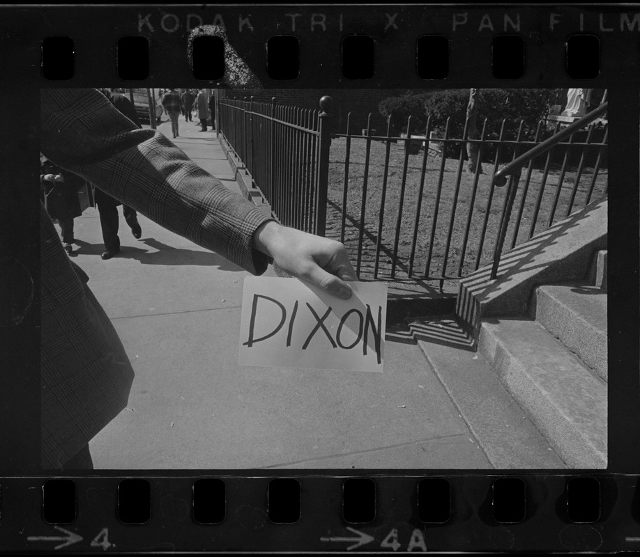 Person holding sign reading "Dixon" on street - Digital Commonwealth
