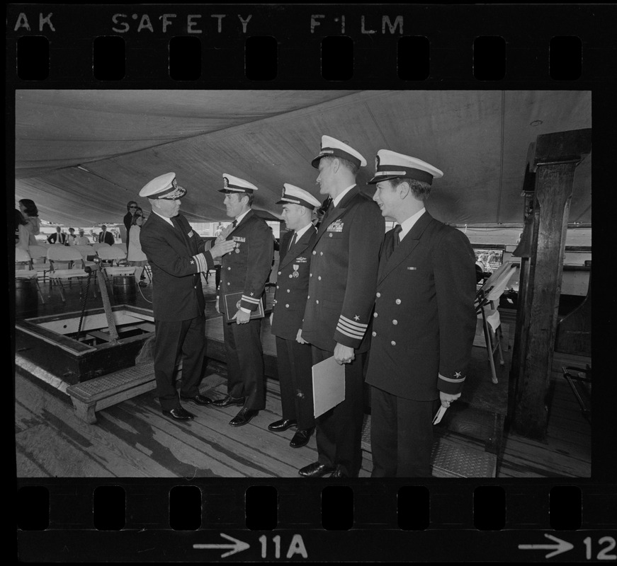 Rear Adm. Joseph Wylie presents medals to four Navy officers aboard his ...