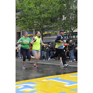 Two runners holding hands alongside another runner at the "One Run ...