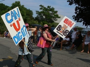 Parade marchers carrying signs reading 'Can U dig it?' and 'Ban the ...