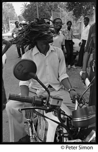 Dillinger (reggae musician), seated on a motorcycle, shaking his ...