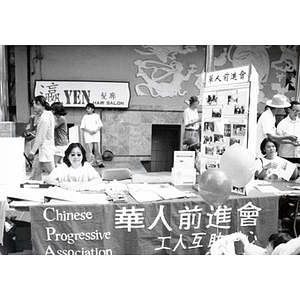 Two women at a table for the Chinese Progressive Association in front ...
