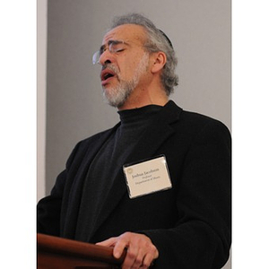 Professor Joshua Jacobson singing from behind a podium at the Holocaust ...