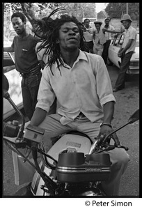 Dillinger (reggae musician), seated on a motorcycle, shaking his ...