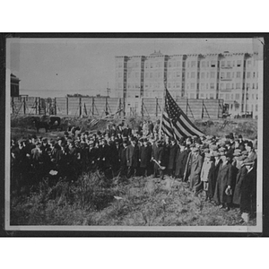 Large group of people gather together on a field with an American flag ...