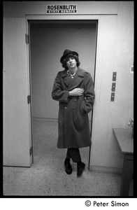 Peter Simon, standing in a doorway, wearing a fedora and trenchcoat ...
